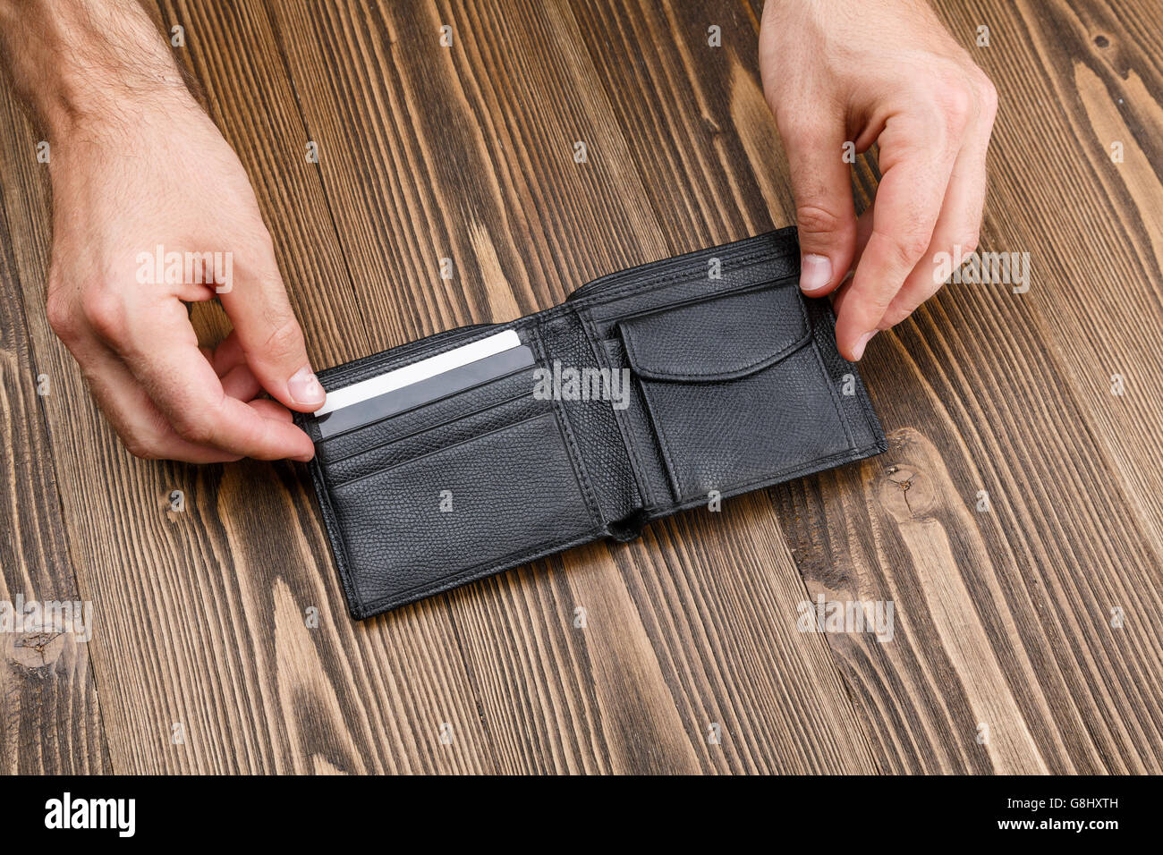 Black man's wallet in man hands over dark wooden background Stock Photo ...
