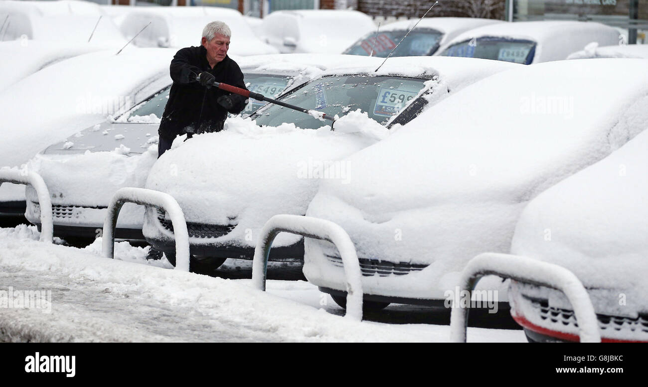 A man clears snow from cars in a garage forecourt after heavy snow at ...