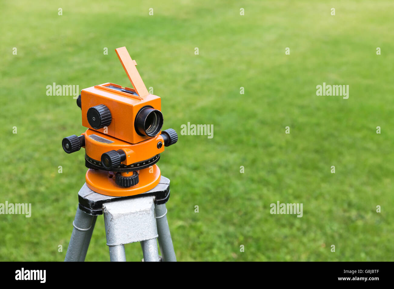 Surveying measuring equipment level transit on tripod on green grass ...