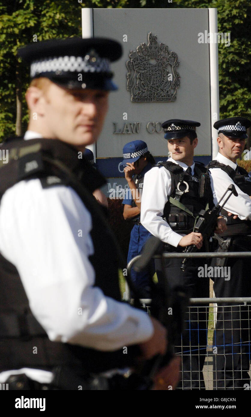 Armed police stand outside as a police van arrives with three of the ...
