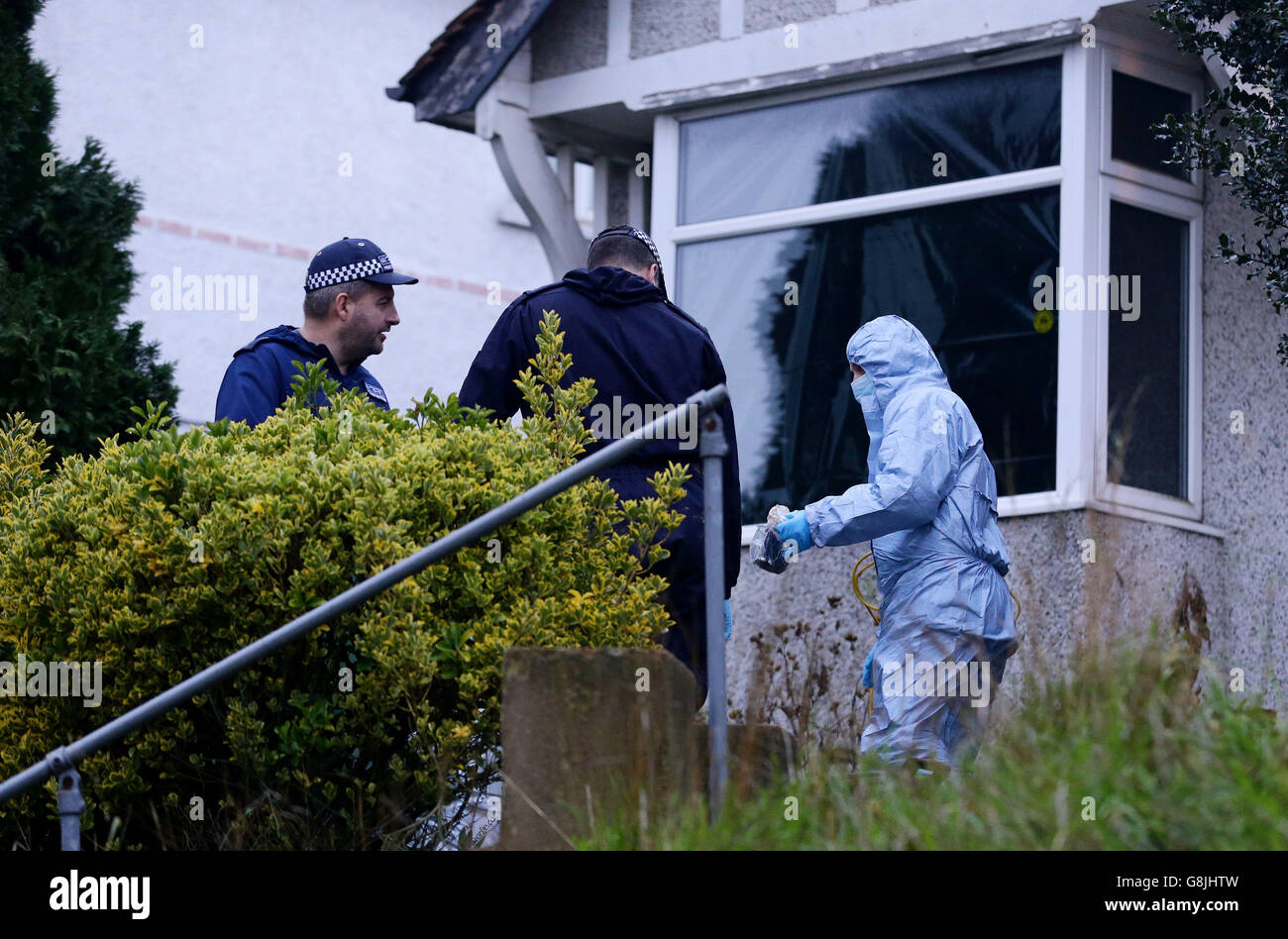 Police search officers investigate the front garden of the house in ...