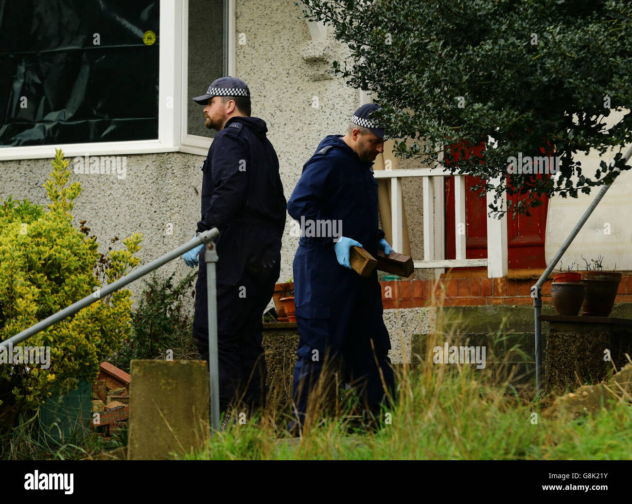 Police search officers investigate the front garden of the house in ...