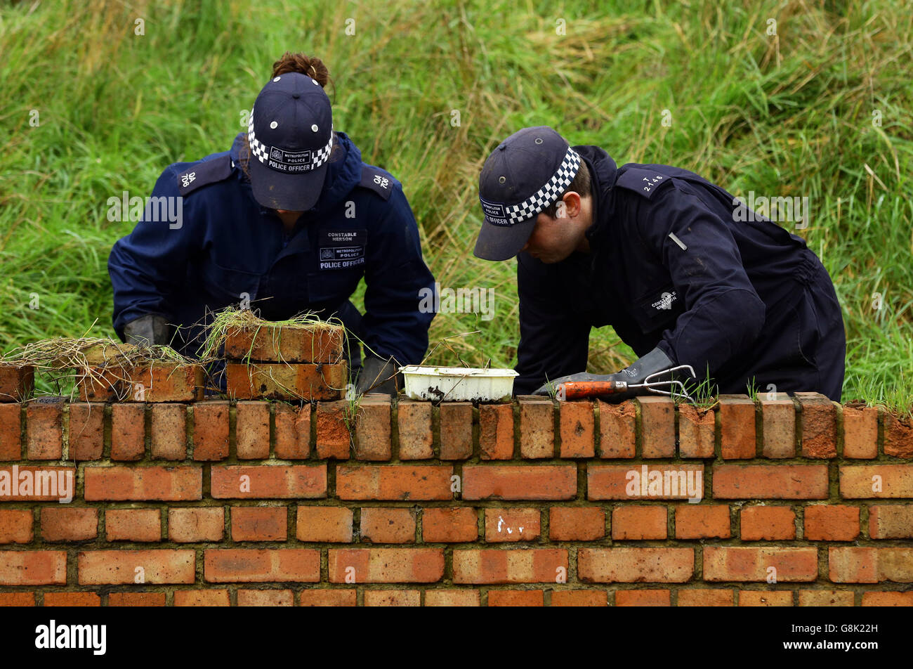 Police search officers investigate the front garden of the house in ...
