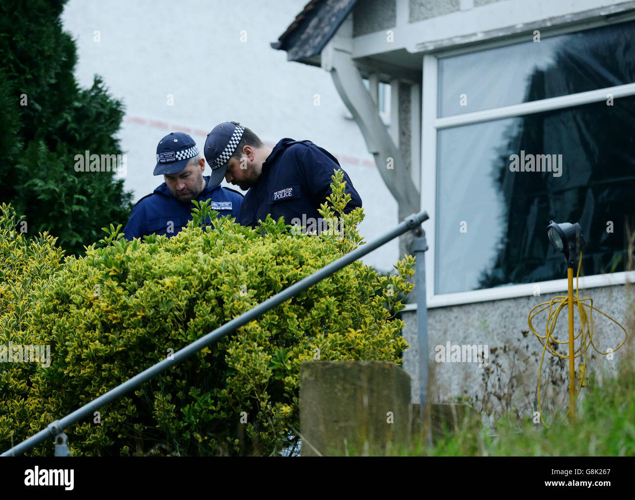 Police search officers investigate the front garden of the house in ...