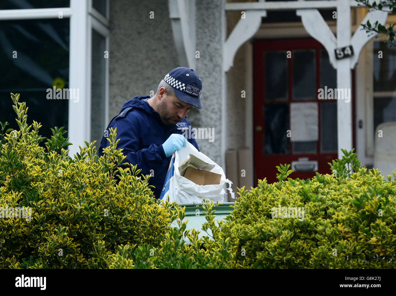 Police search officers investigate the front garden of the house in ...