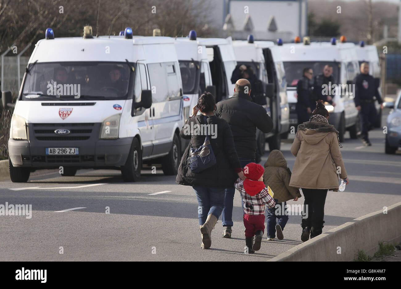 Migrants walk past French police vans outside The Jungle refugee camp ...
