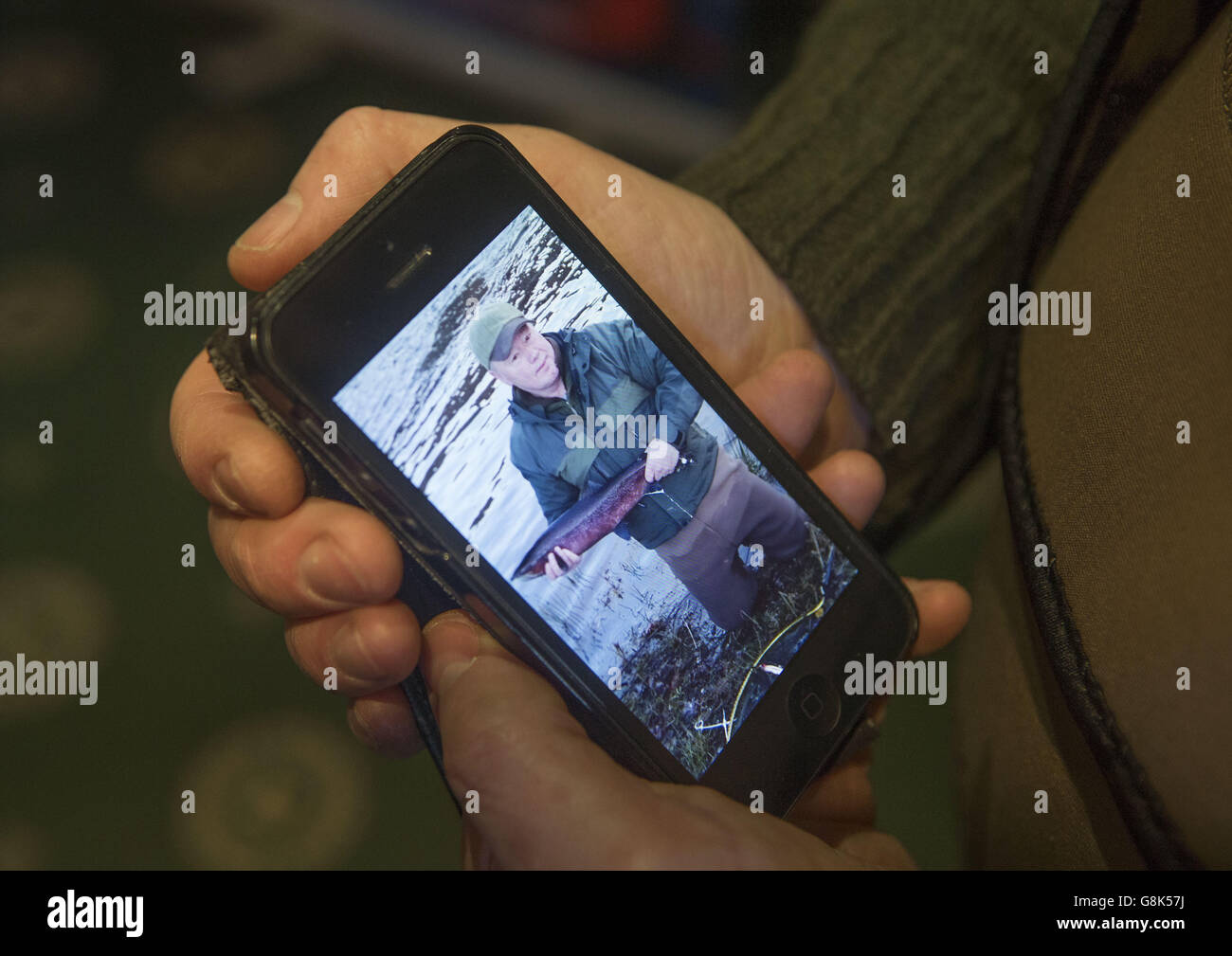 An angler views his catch on a mobile phone after fishing on the River ...