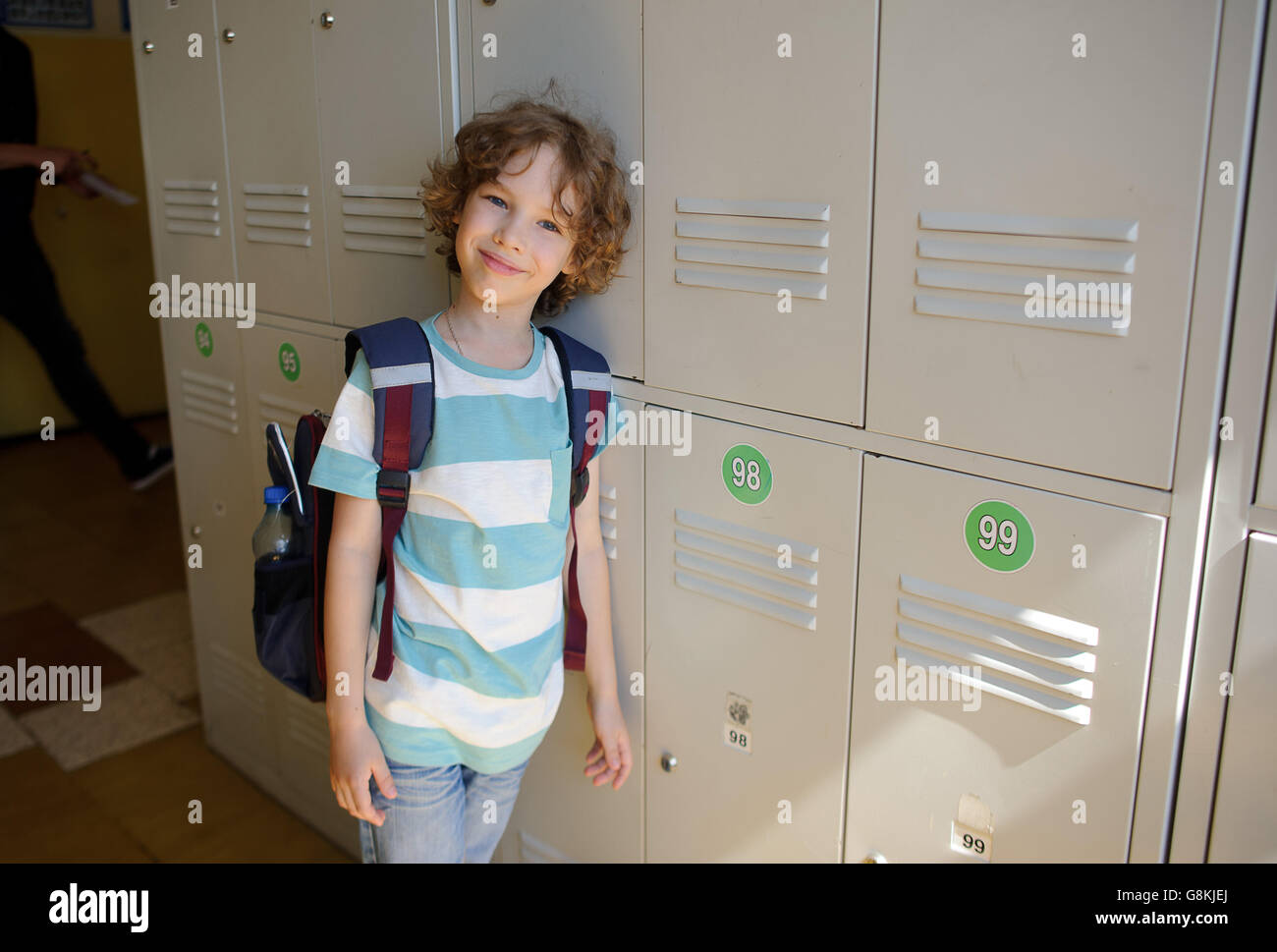 Little schoolboy standing near lockers in school hallway. He leaned ...