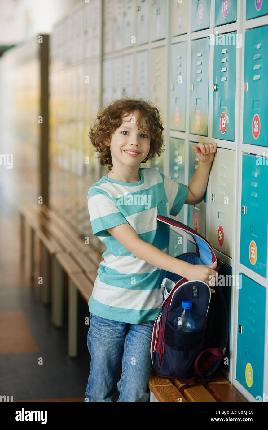 The schoolboy standing near lockers in school hallway. He opened the ...