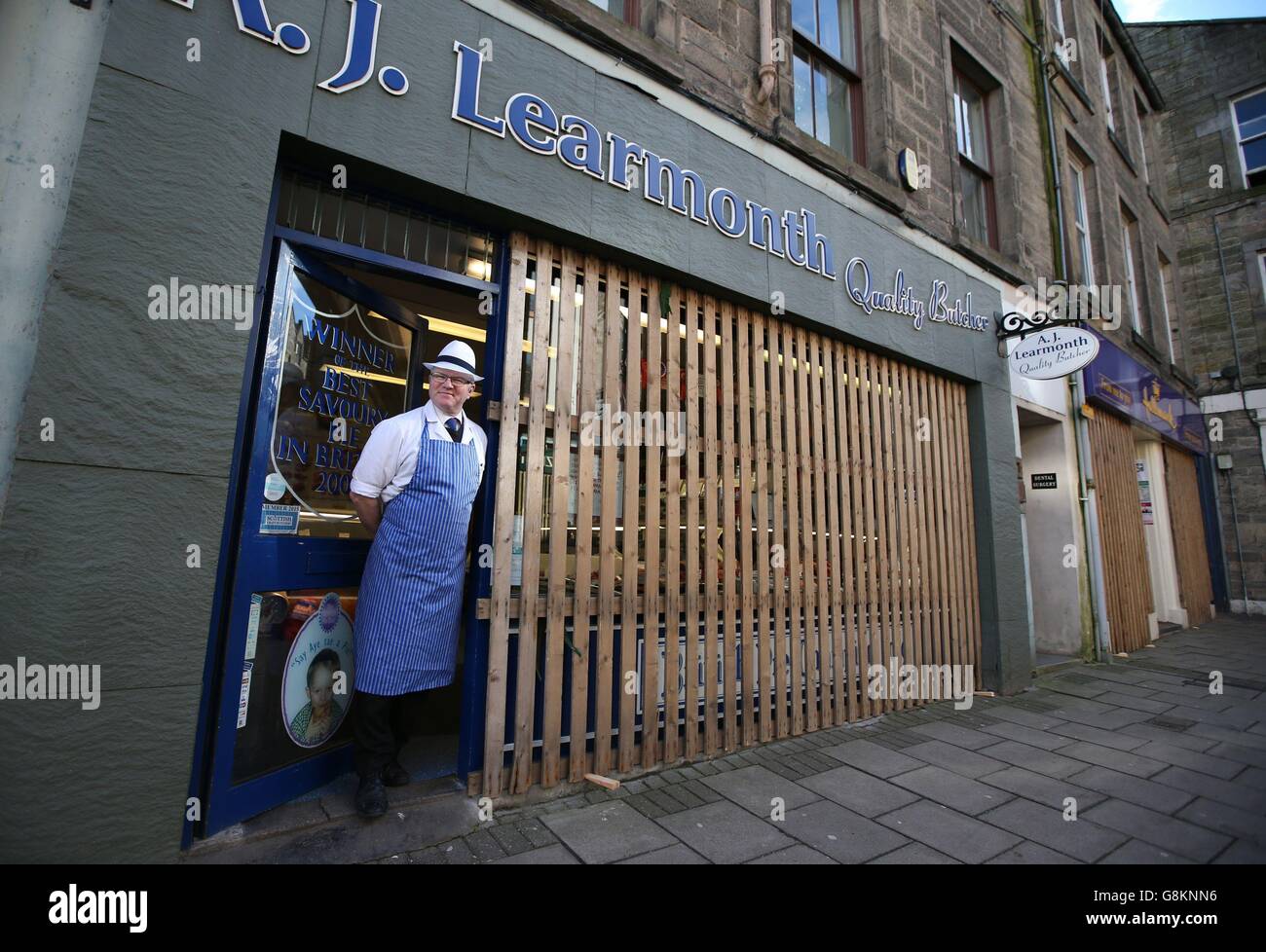 A butcher looks out from his shop with its windows boarded up ahead of ...