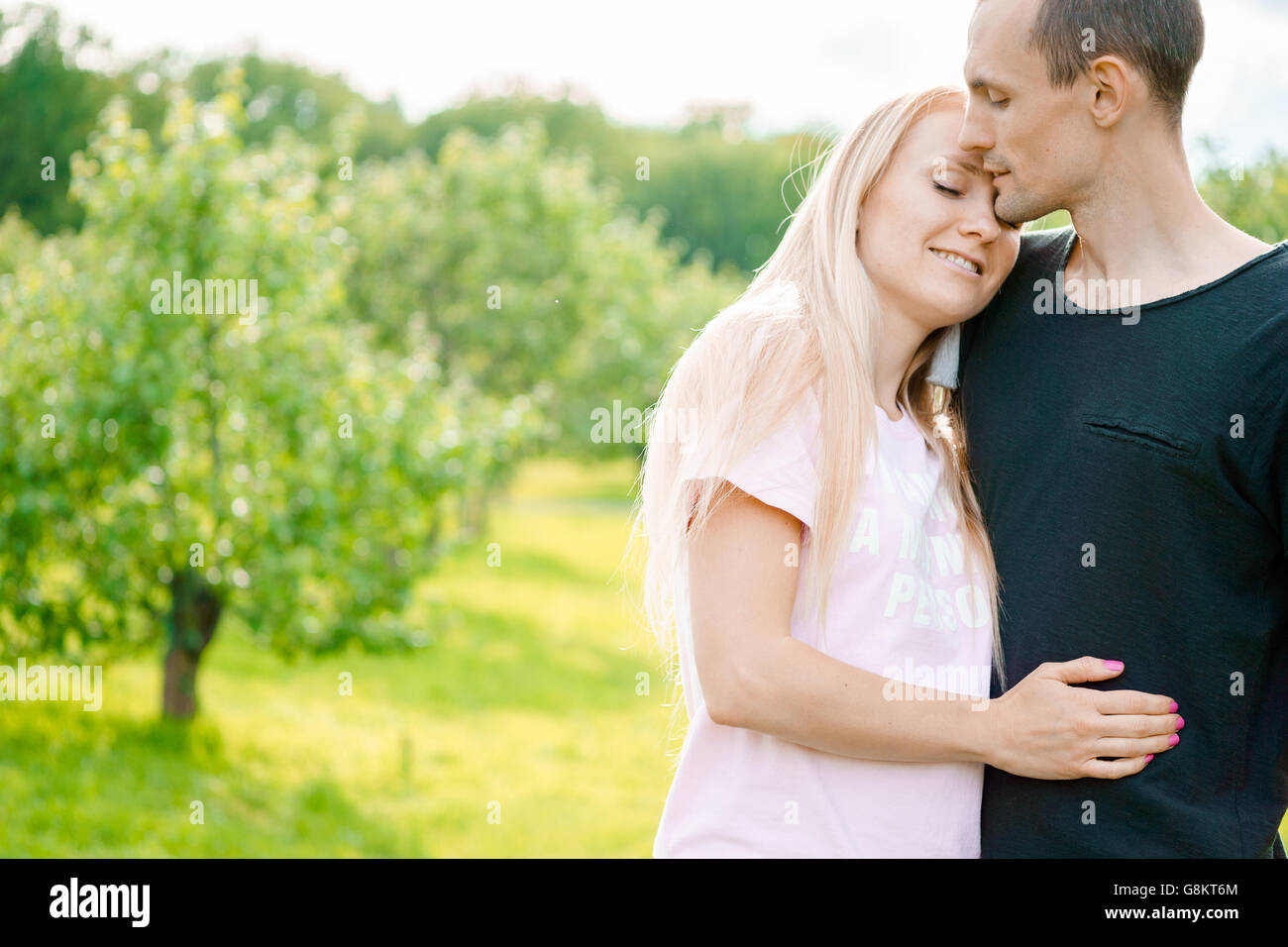 Couple standing in park and hugging Stock Photo - Alamy
