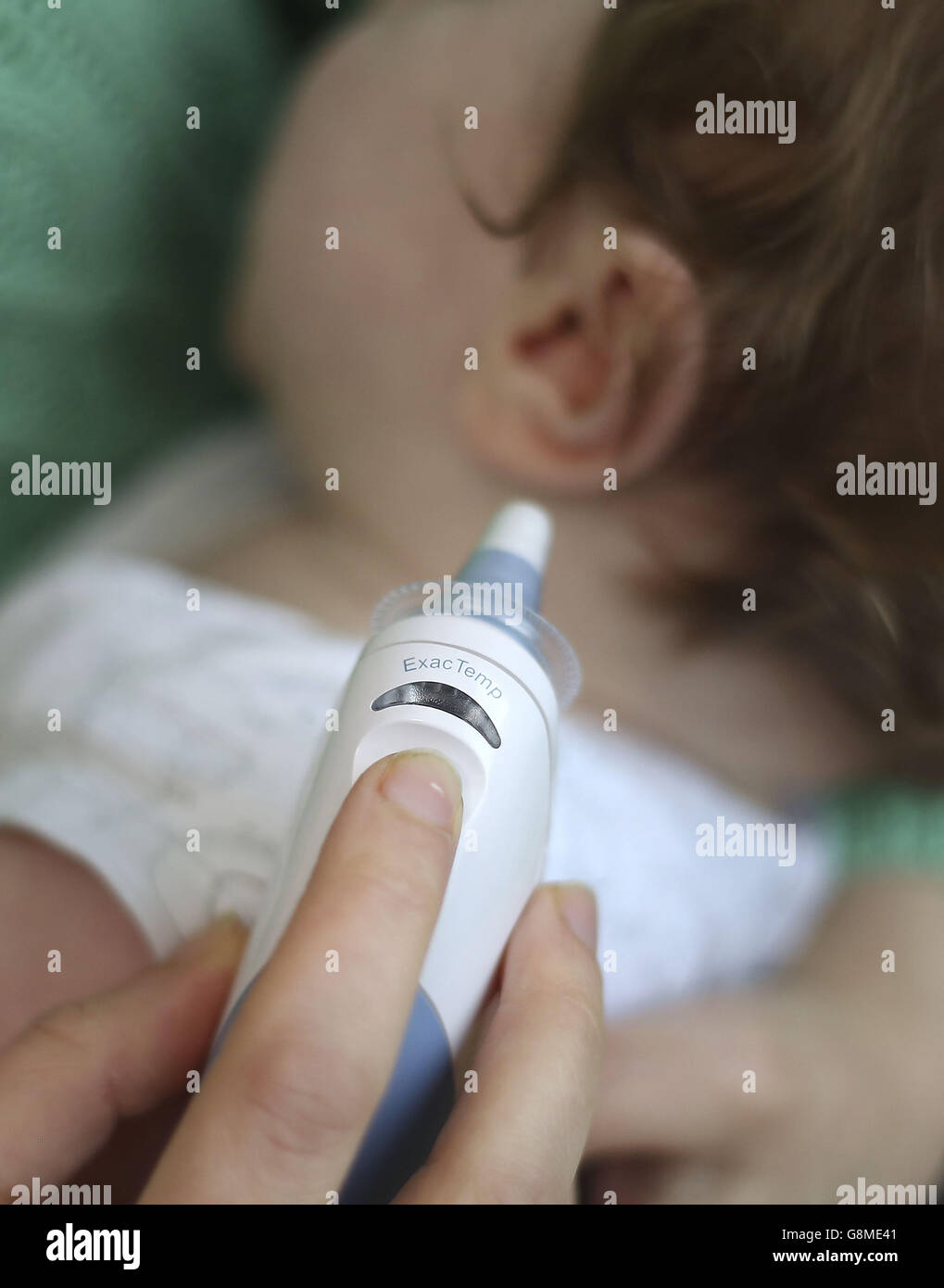 An eight month old baby boy having his temperature taken with a digital ...