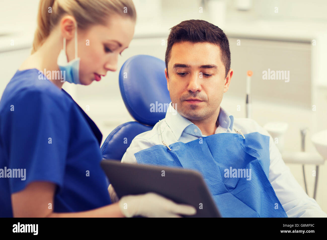 female dentist with tablet pc and male patient Stock Photo - Alamy