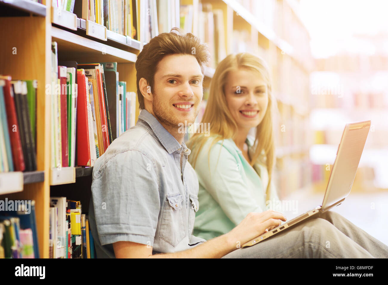 happy students with laptop in library Stock Photo - Alamy