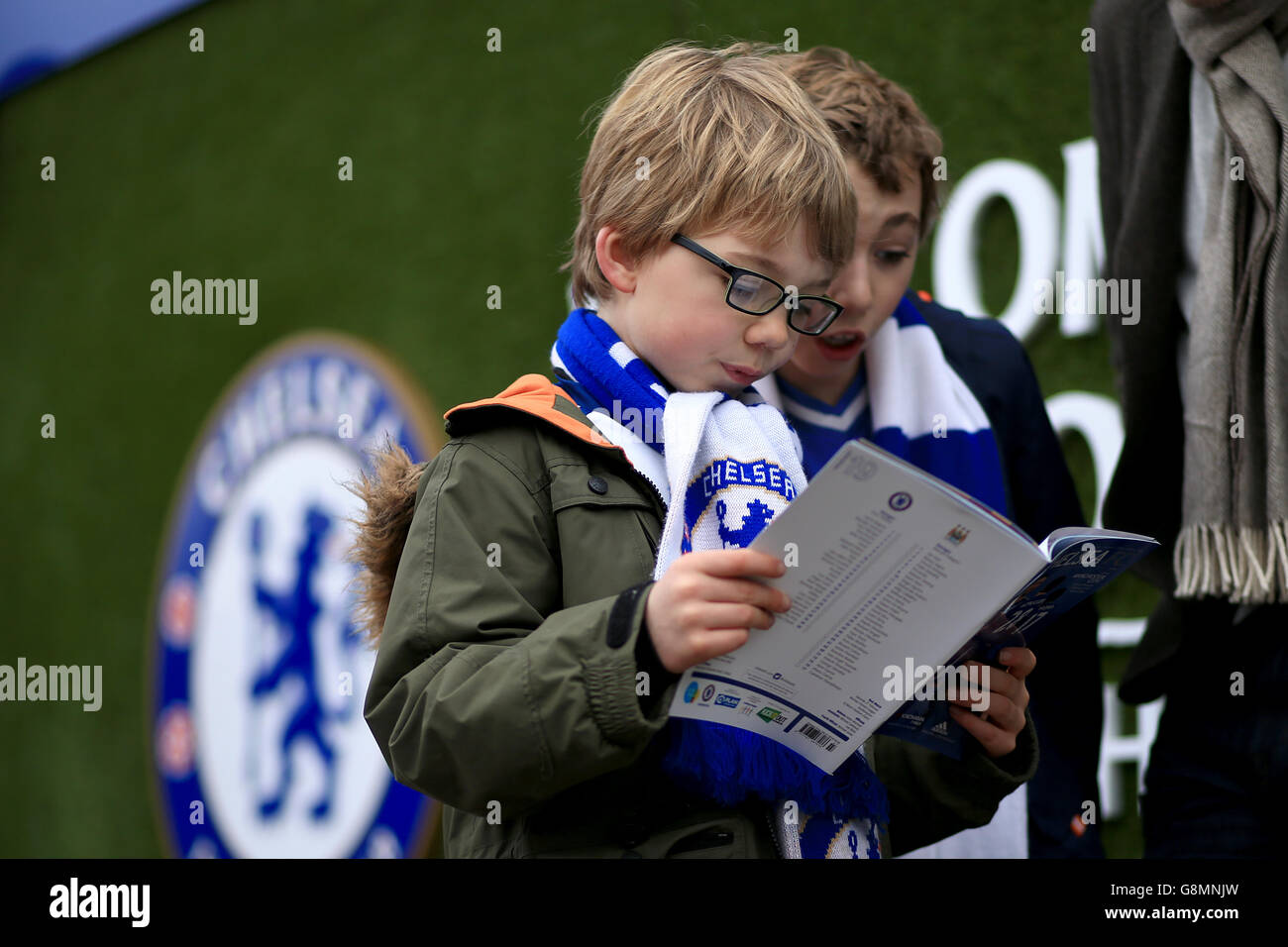 Young Chelsea fans read the match day programme outside the ground ...