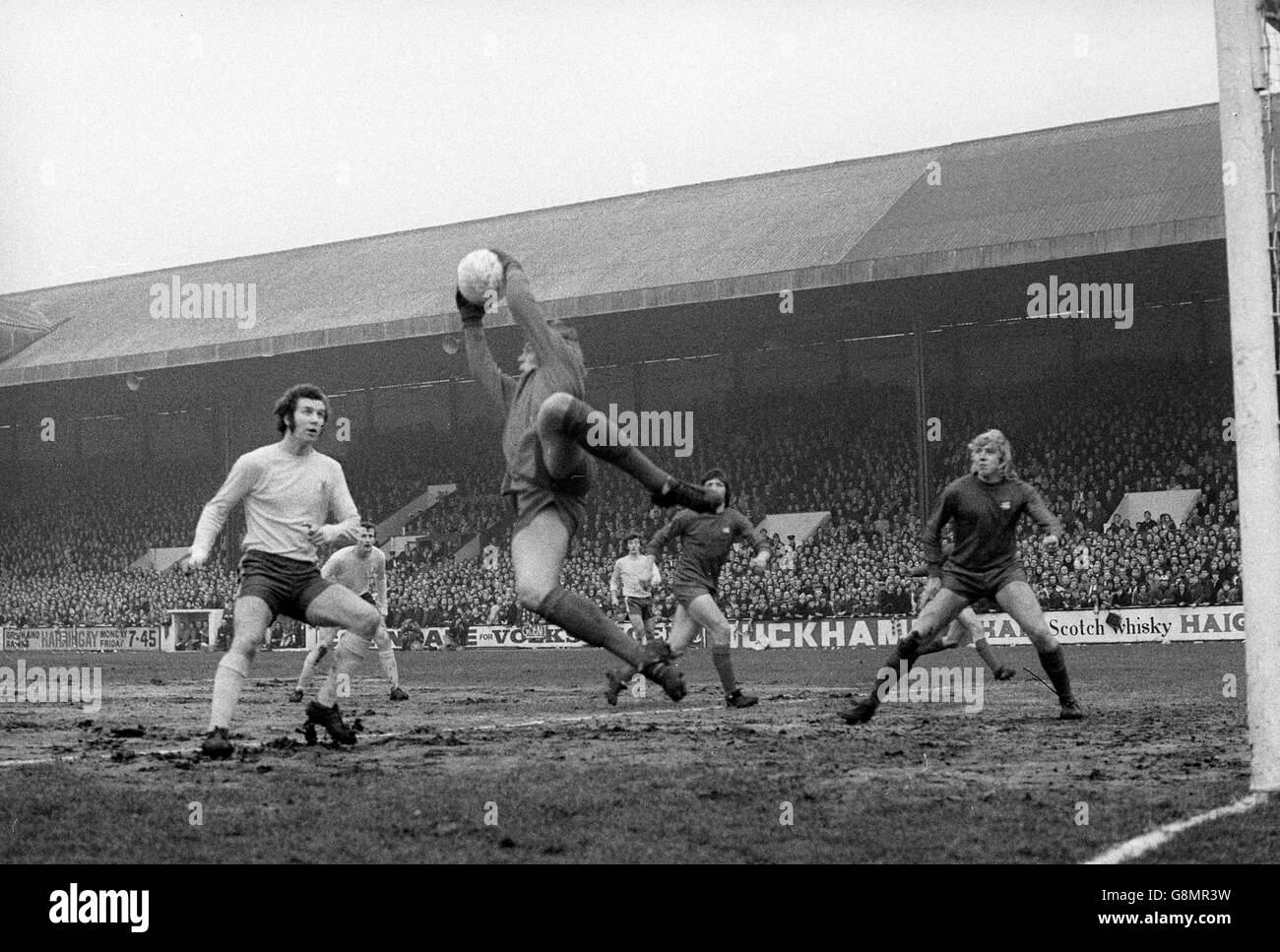 Leyton Orient goalkeeper Ray Goddard jumps for the ball, watched by ...