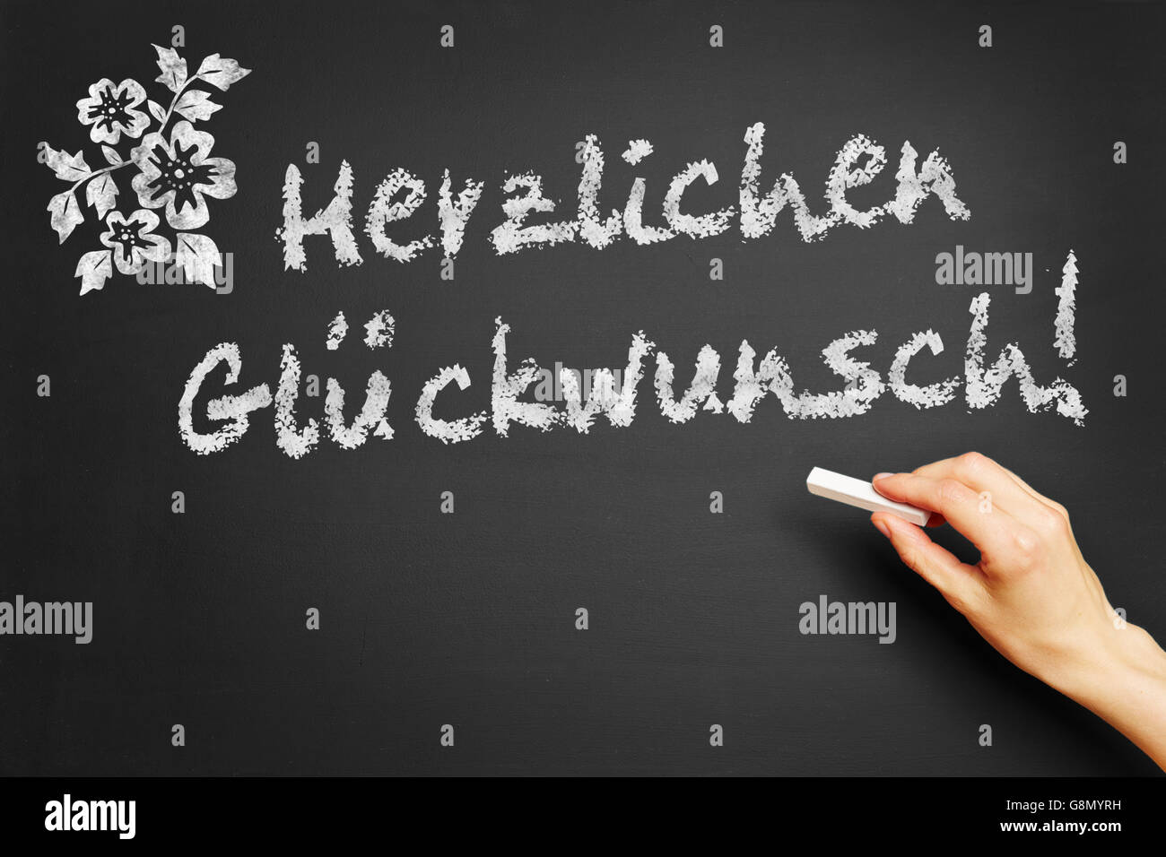 Hand writes in German "Herzlichen Glückwunsch!" (Congratulations) on ...
