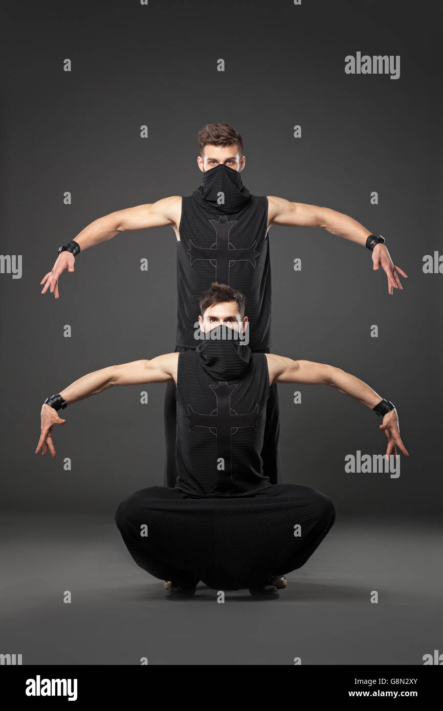 Two male dancers dancing in ninja costumes against gray background ...