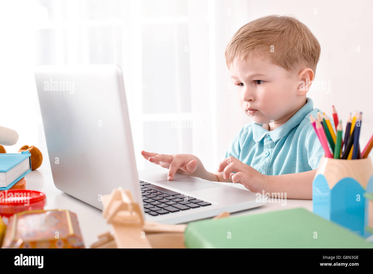 Modern problem: kids and computers. Little boy using laptop. Nice white ...