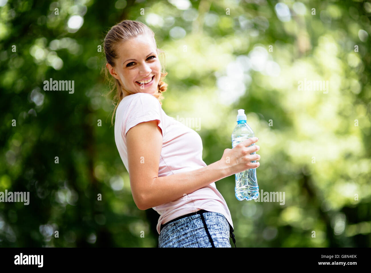 Dehydrated female jogger drinking water Stock Photo - Alamy