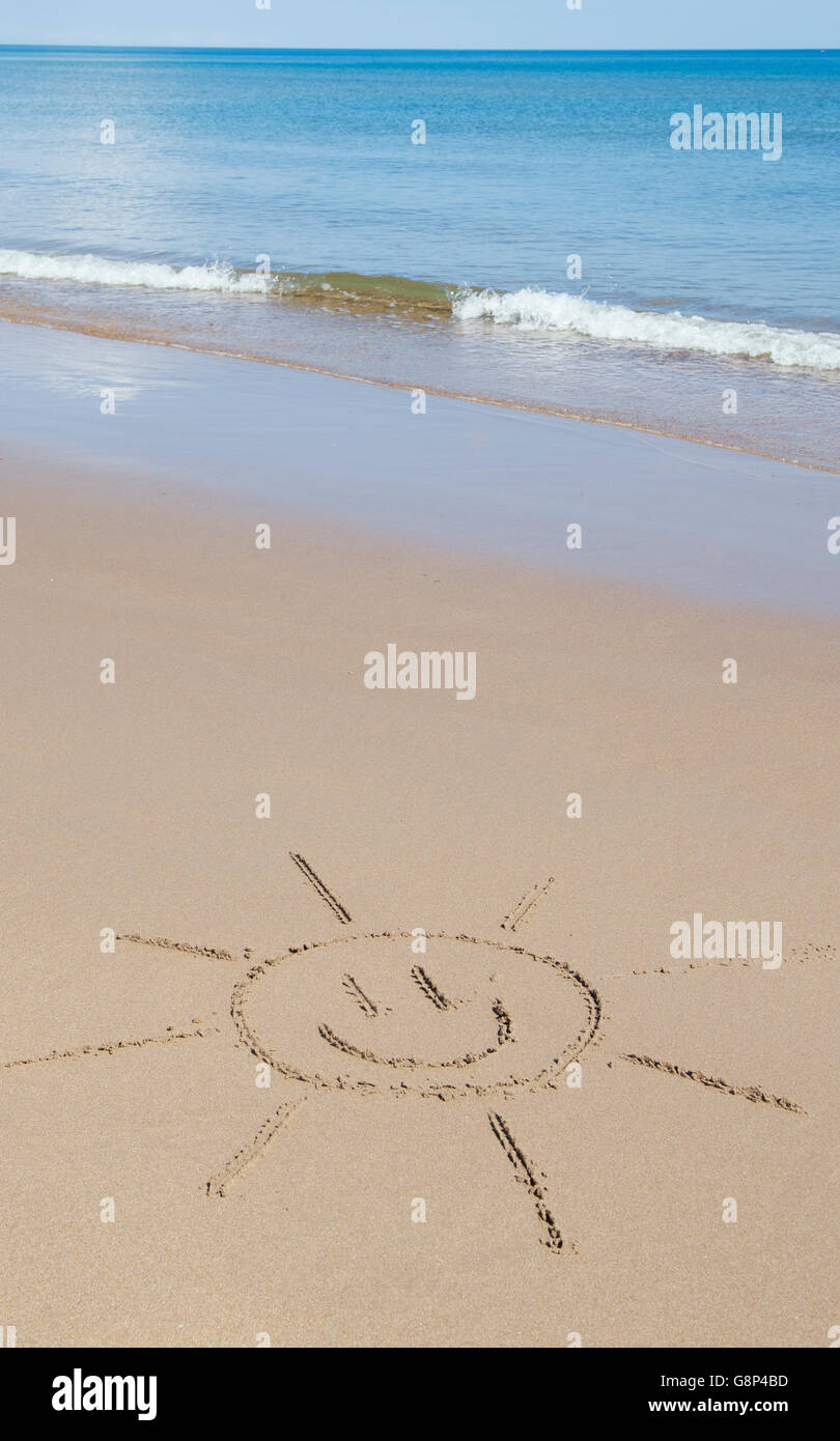 Smiley face sun drawing on a beach. UK Stock Photo - Alamy