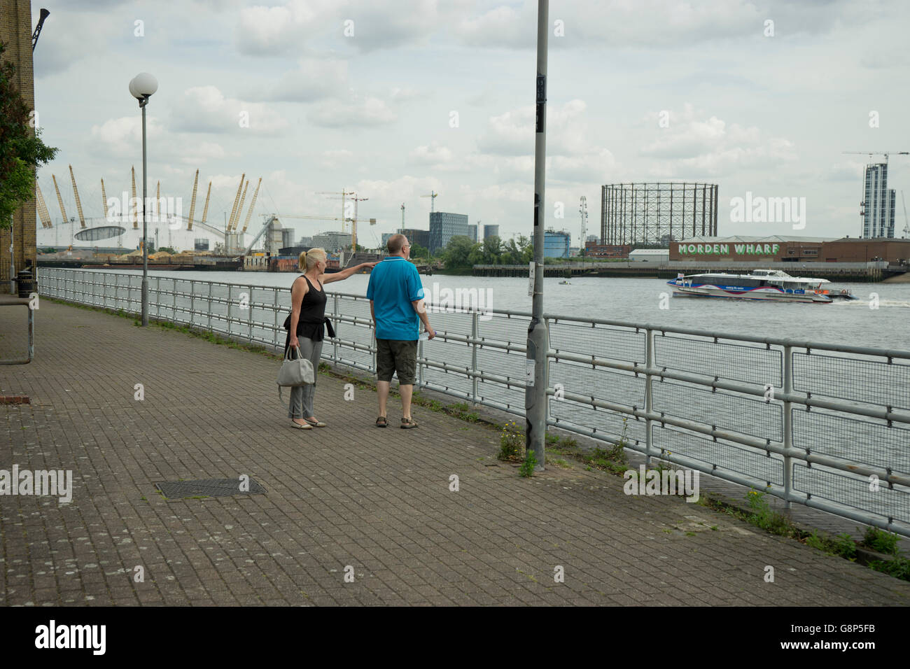 People walk at riverside promenade at new Housing development by river ...