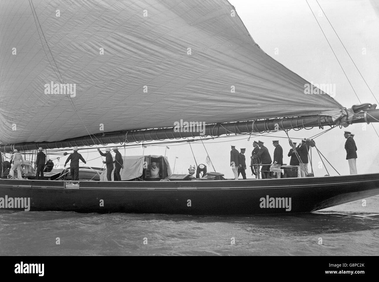 King George V gives a hand with the rope, while Queen Mary looks on ...
