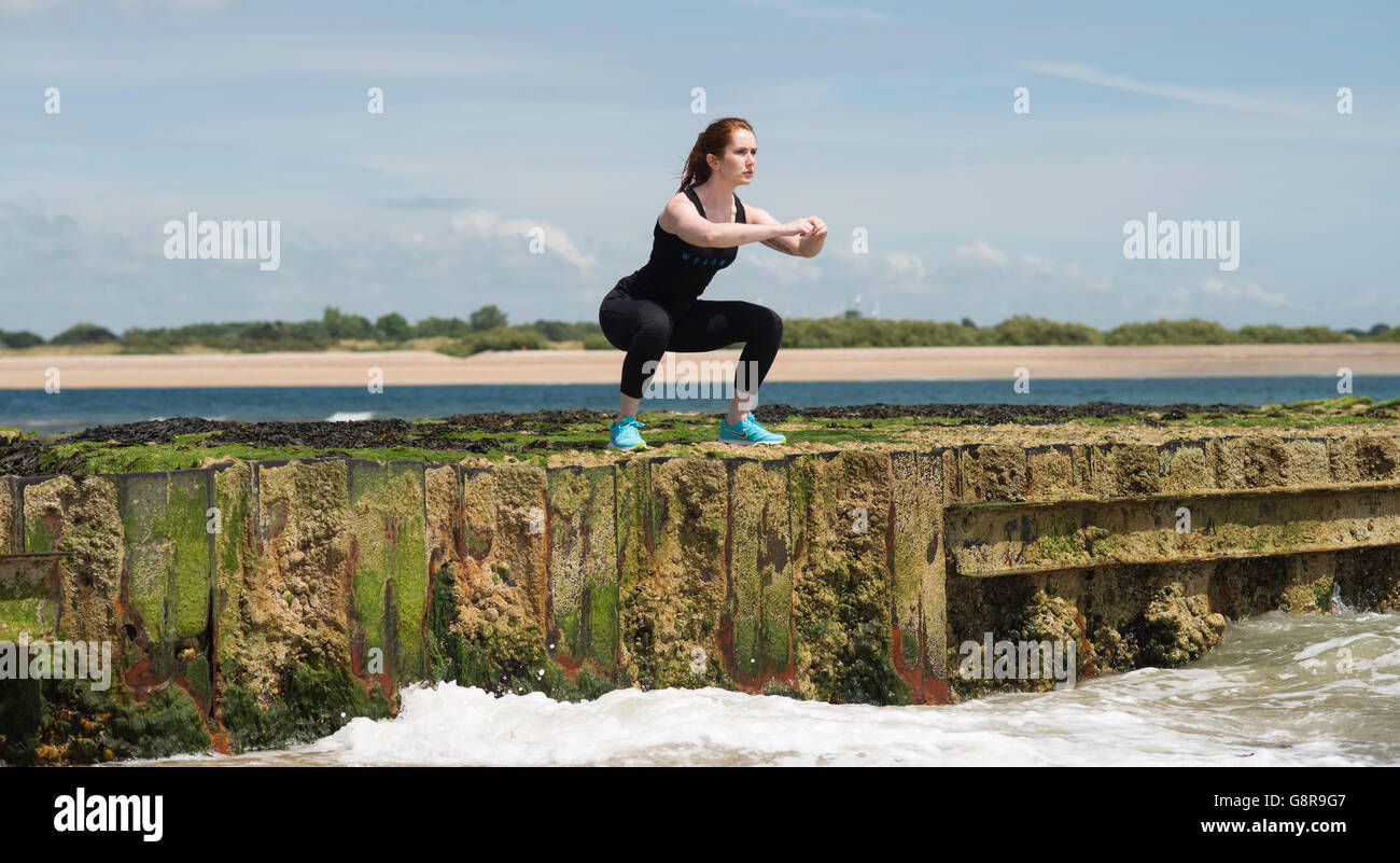 woman doing squats keeping fit by the sea Stock Photo - Alamy