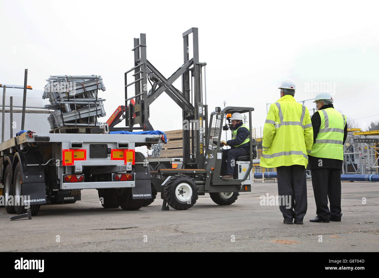 A truck-mounted fork lift truck unloads scaffolding equipment from a ...