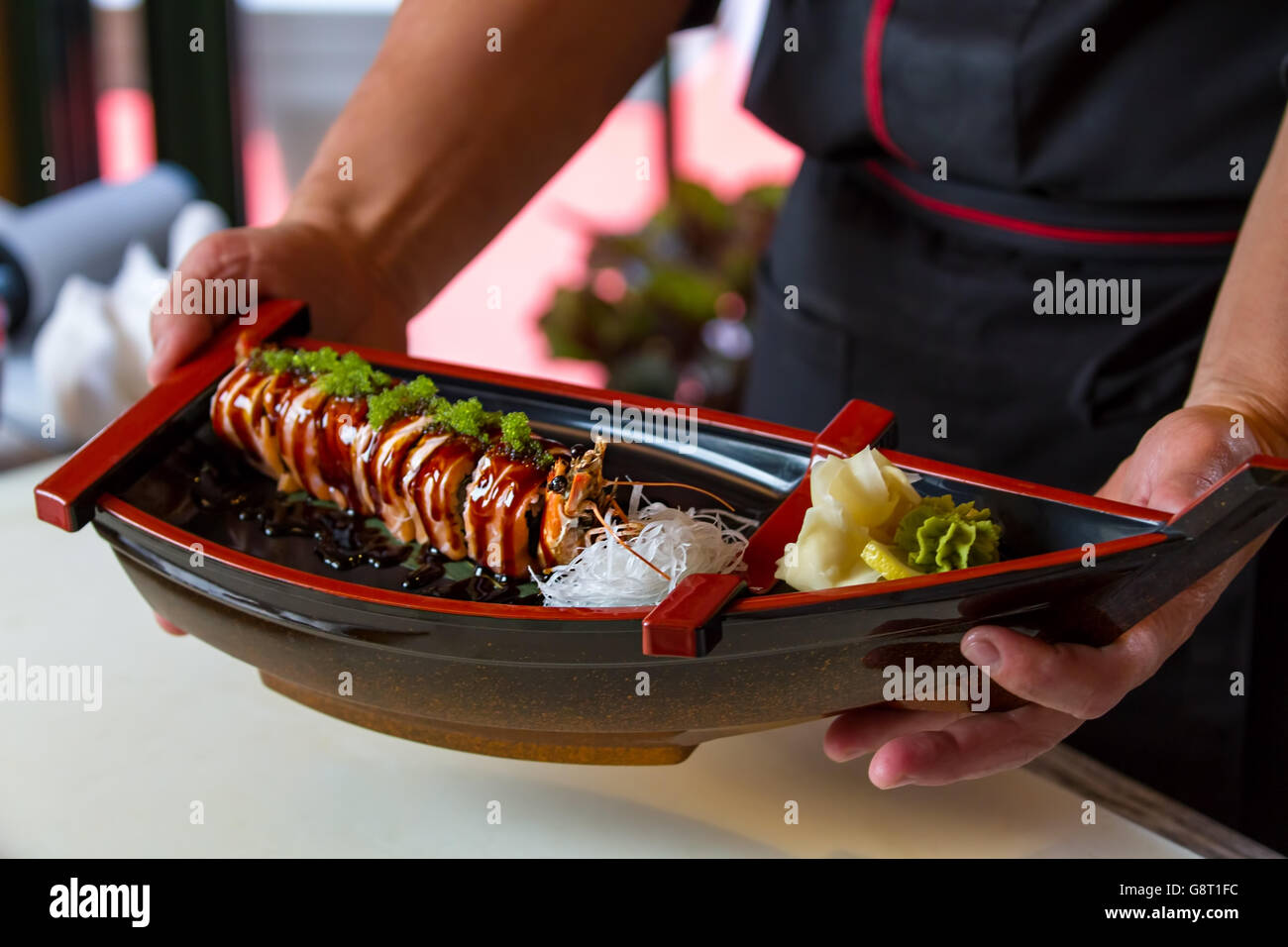 Man's hands hold sushi boat Stock Photo - Alamy