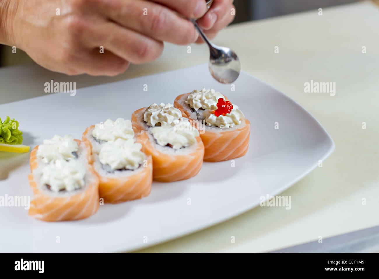 Hand holds spoon over sushi Stock Photo - Alamy