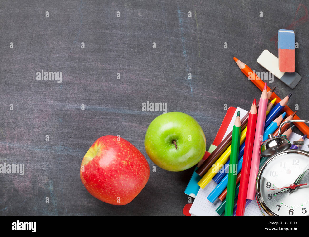 School supplies and apples on blackboard background. Top view with copy ...