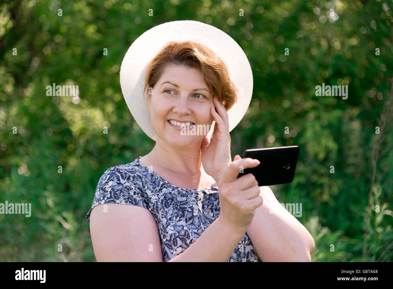 woman in hat with cell phone outside Stock Photo - Alamy