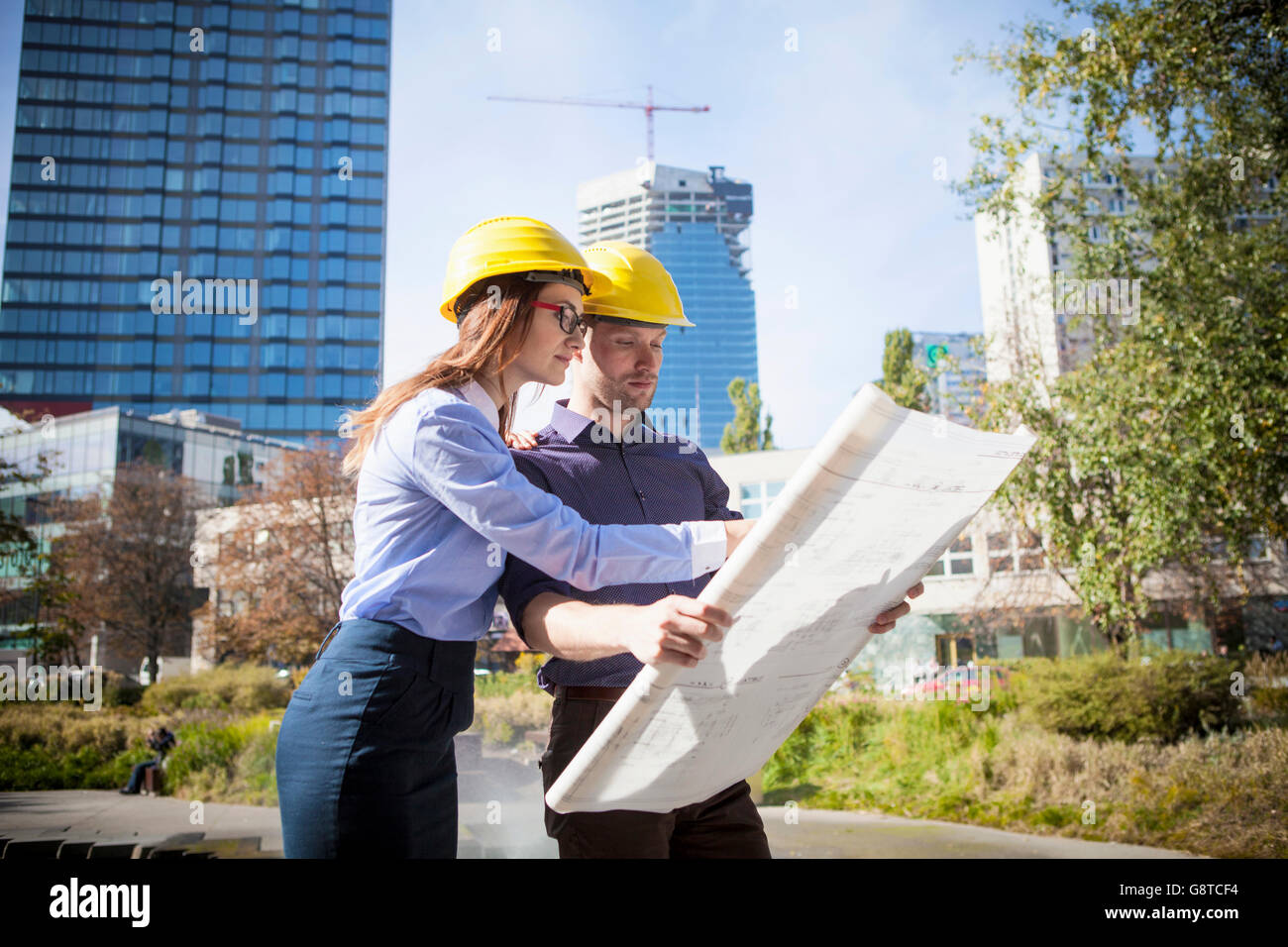 Two architects looking at a blueprint in city Stock Photo - Alamy