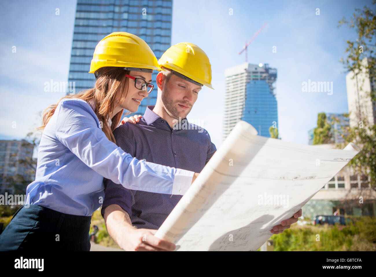 Two architects looking at a blueprint in city Stock Photo - Alamy