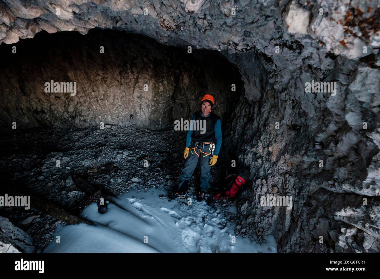 Mountain guide with helmet and backpack standing in cave Stock Photo ...