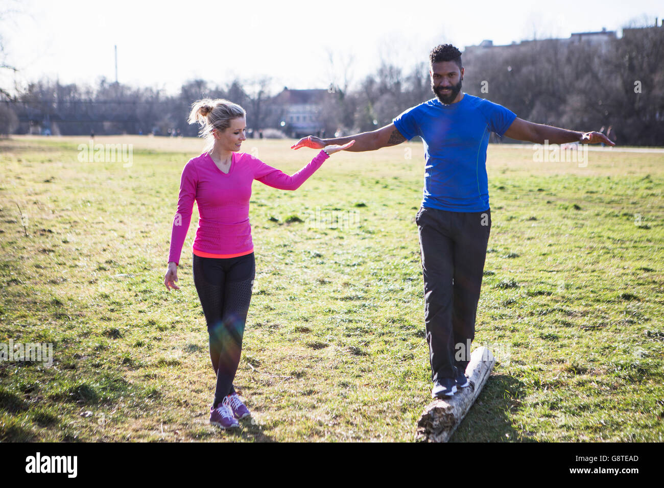 Young couple exercising balance on tree trunk Stock Photo - Alamy