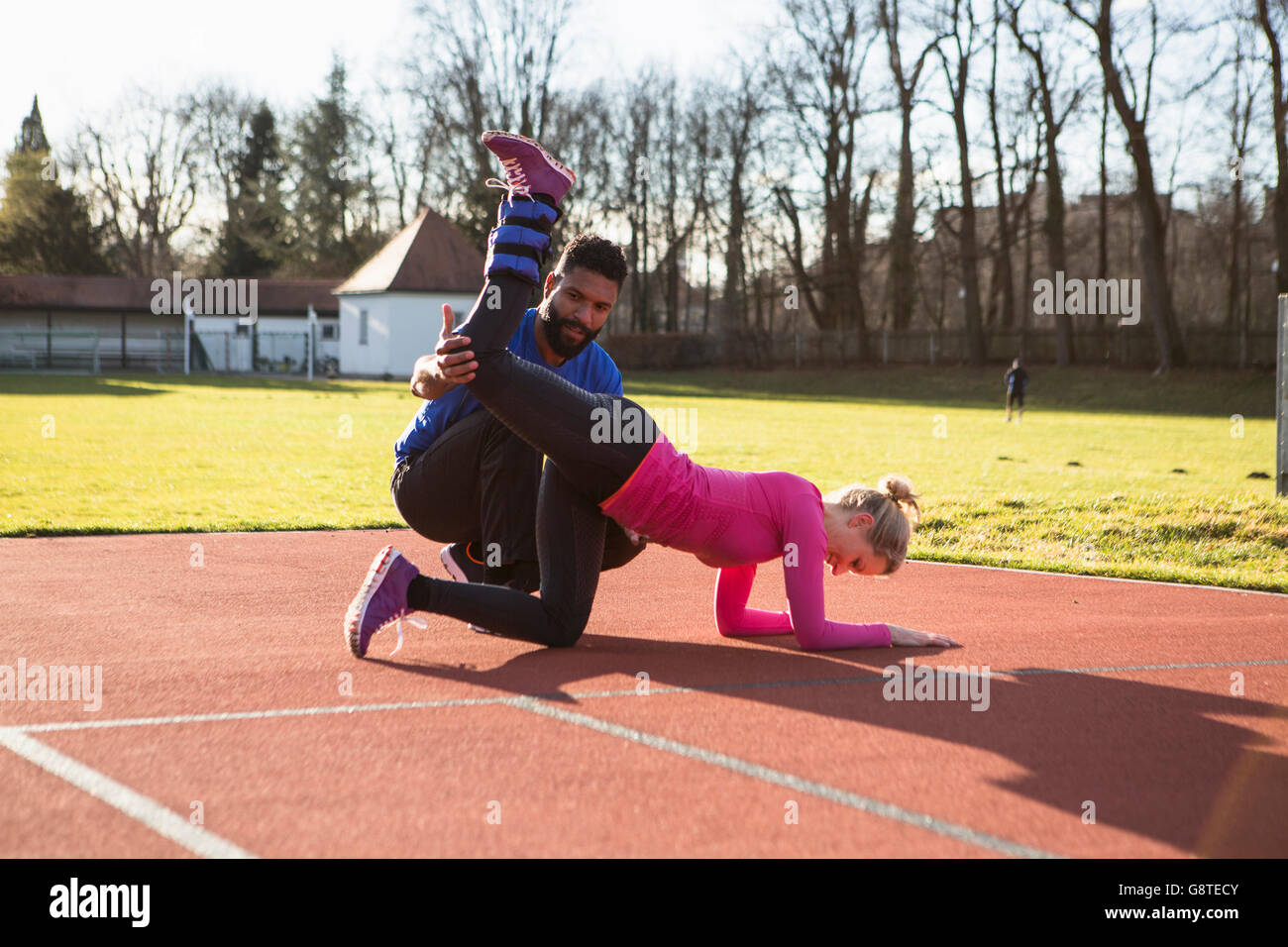 Young woman doing stretching exercise with coach watching Stock Photo ...