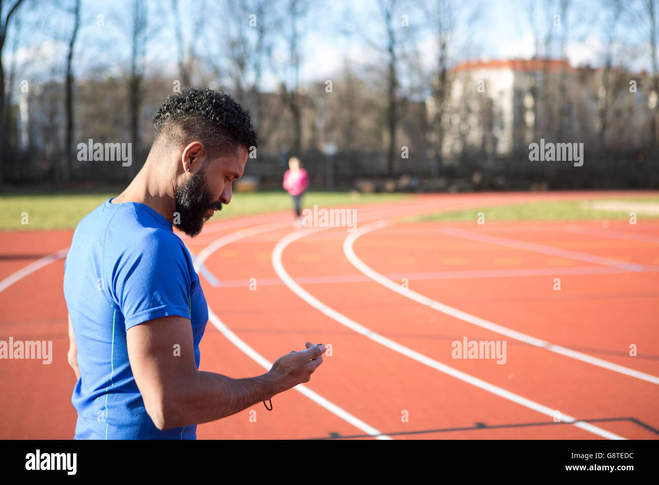 Young woman running on track with coach watching Stock Photo - Alamy