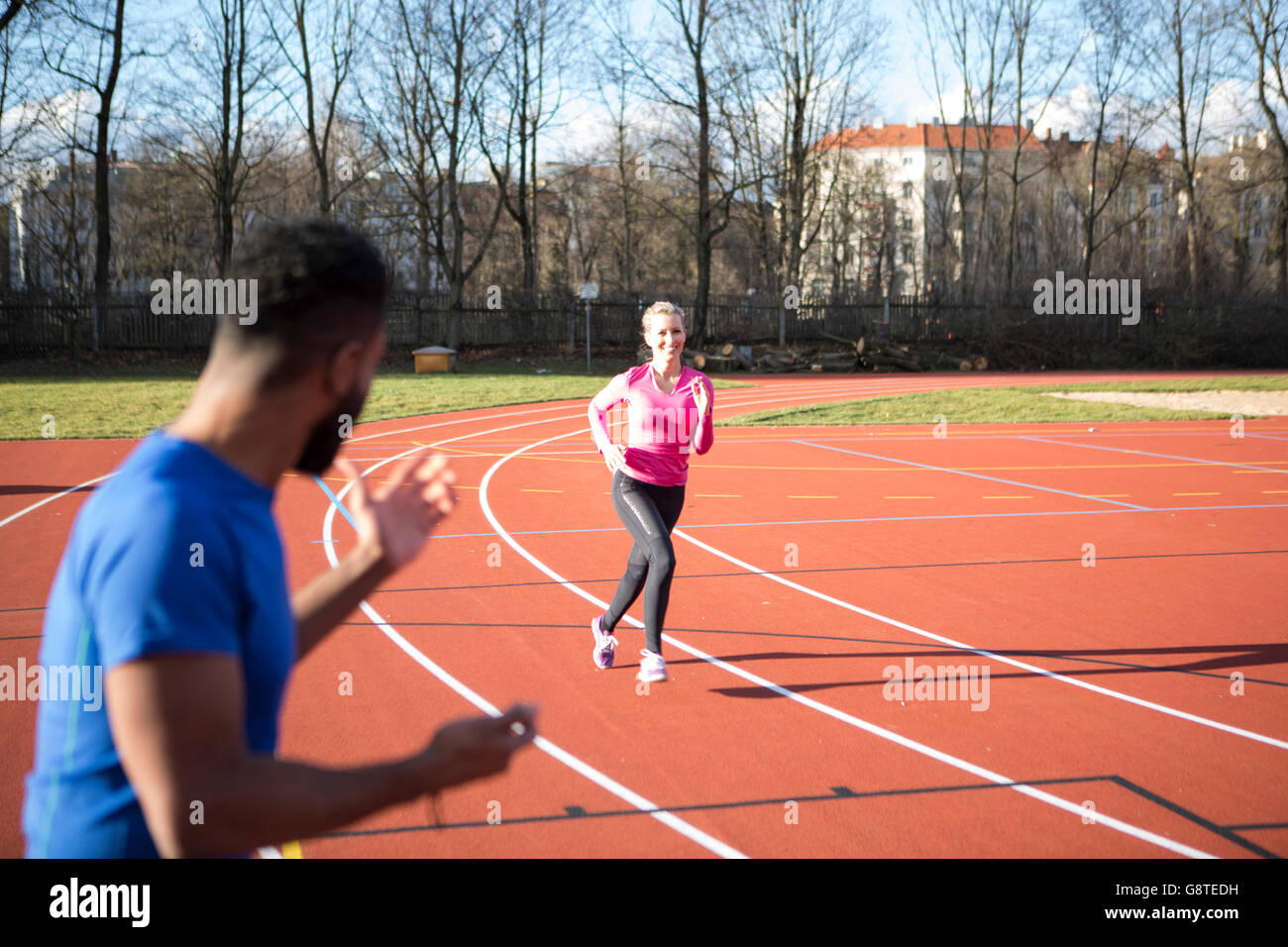 Young woman running on track with coach watching Stock Photo - Alamy