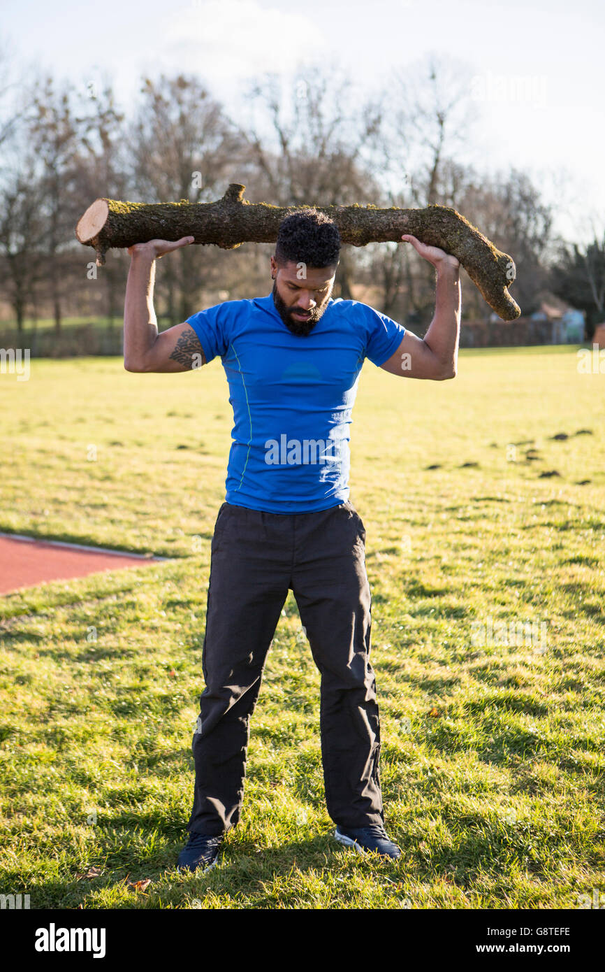 Young man doing squats with tree trunk on shoulder Stock Photo - Alamy
