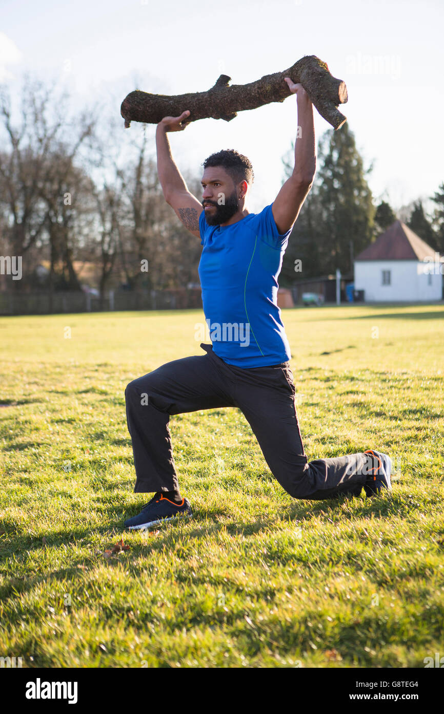 Young man doing squats with tree trunk on shoulder Stock Photo - Alamy