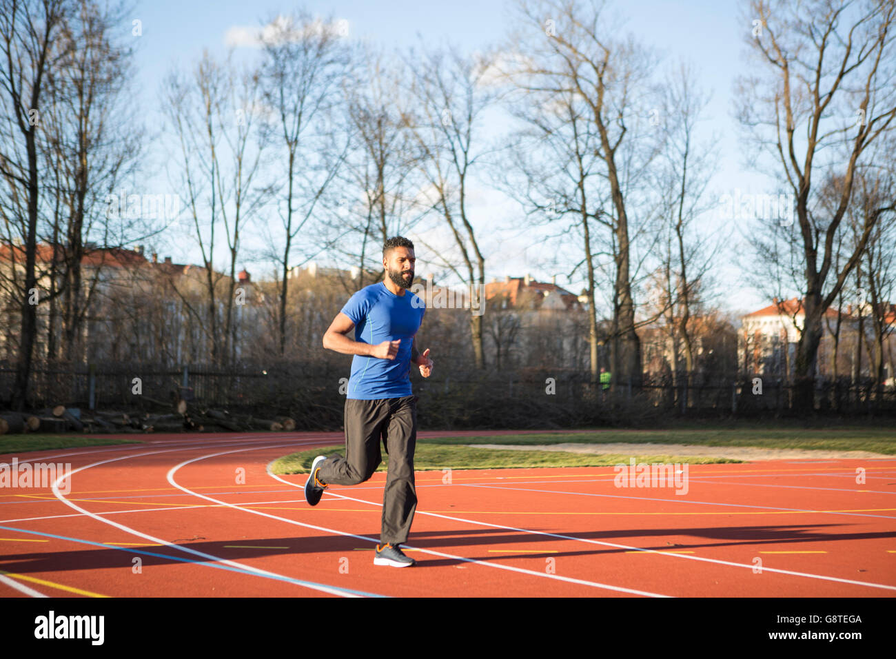 Young man jogging on running track in stadium Stock Photo - Alamy