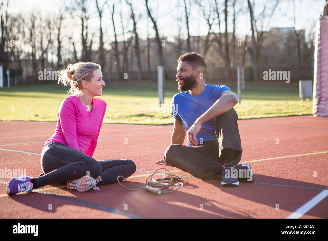 Woman sits on running track talking to coach Stock Photo - Alamy