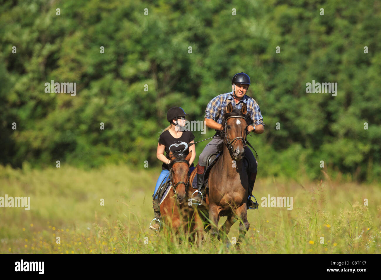 Couple horseback riding in field Stock Photo - Alamy
