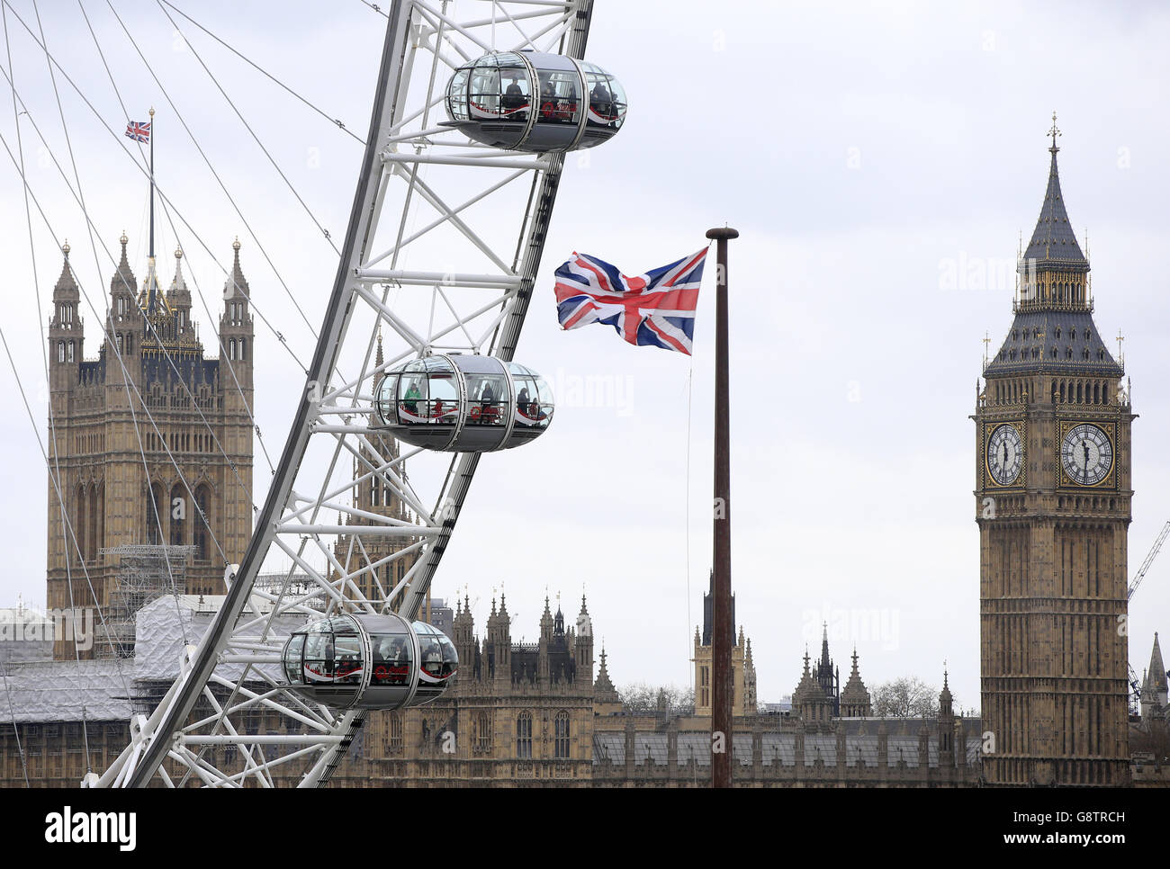 Visitors ride on the London Eye with the Palace of Westminster in the ...