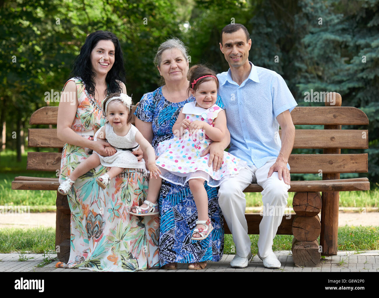 big family sit on wooden bench in city park, summer season, child ...