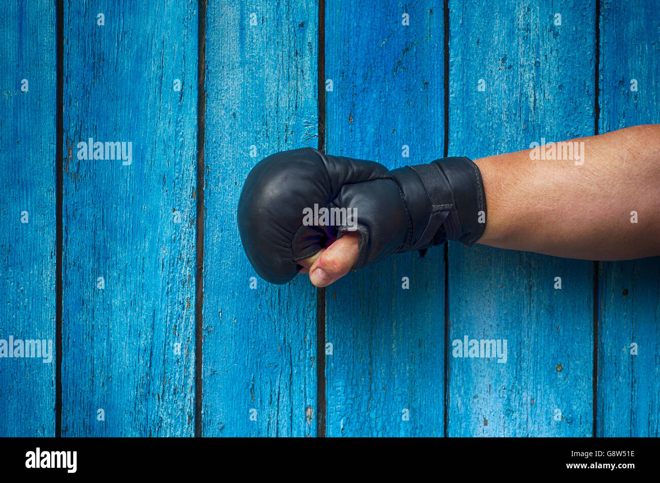 right hand of the man in black boxing gloves on a blue retro wooden ...