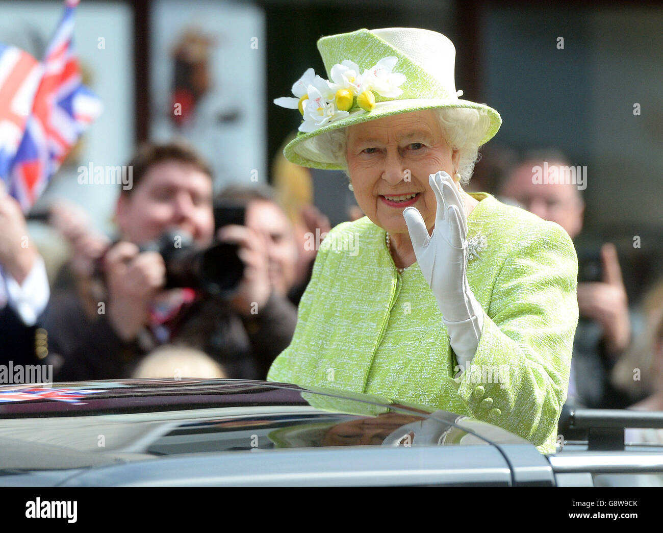 Queen Elizabeth II waves to well wishers from a open top Range Rover in ...
