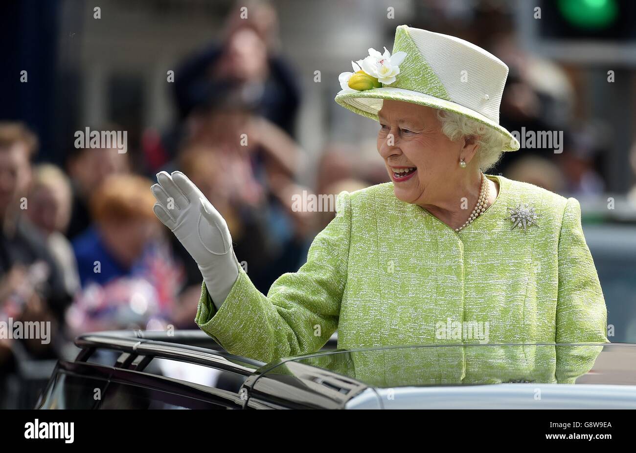 Queen Elizabeth II waves to well wishers from a open top Range Rover in ...